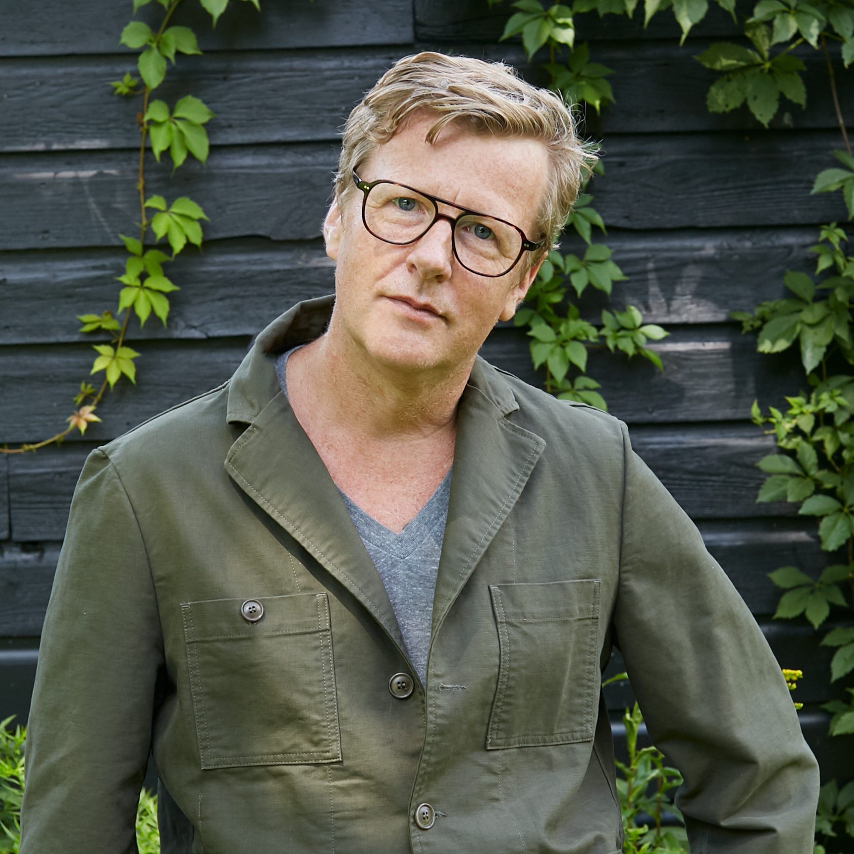 man with light, cropped hair, wearing glasses and a sport jacket.